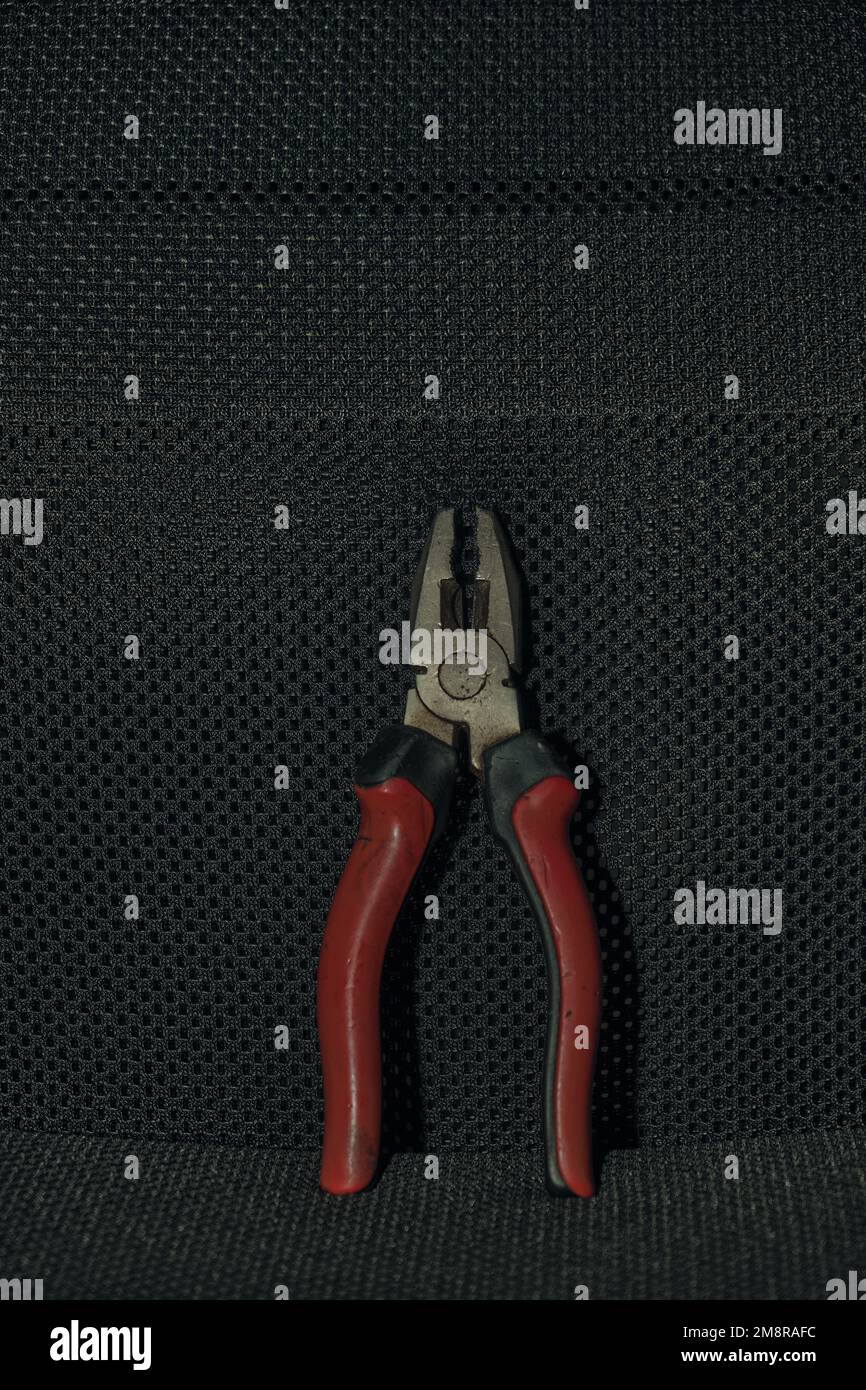 Pliers Open metal nippers with a red and green handle isolated on black ...