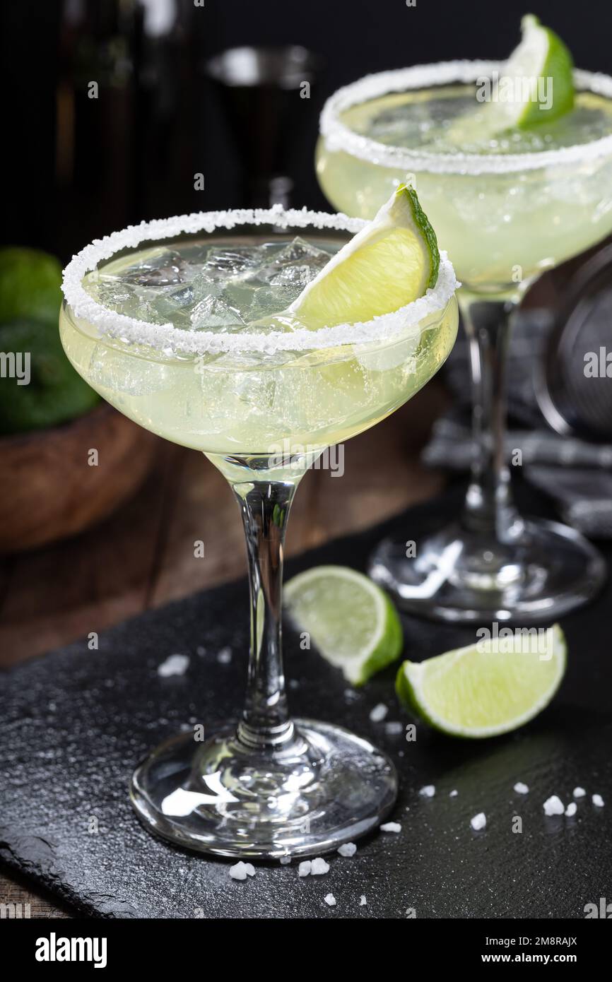 Margarita cocktail with ice, lime and salt rim on a black slate board ...