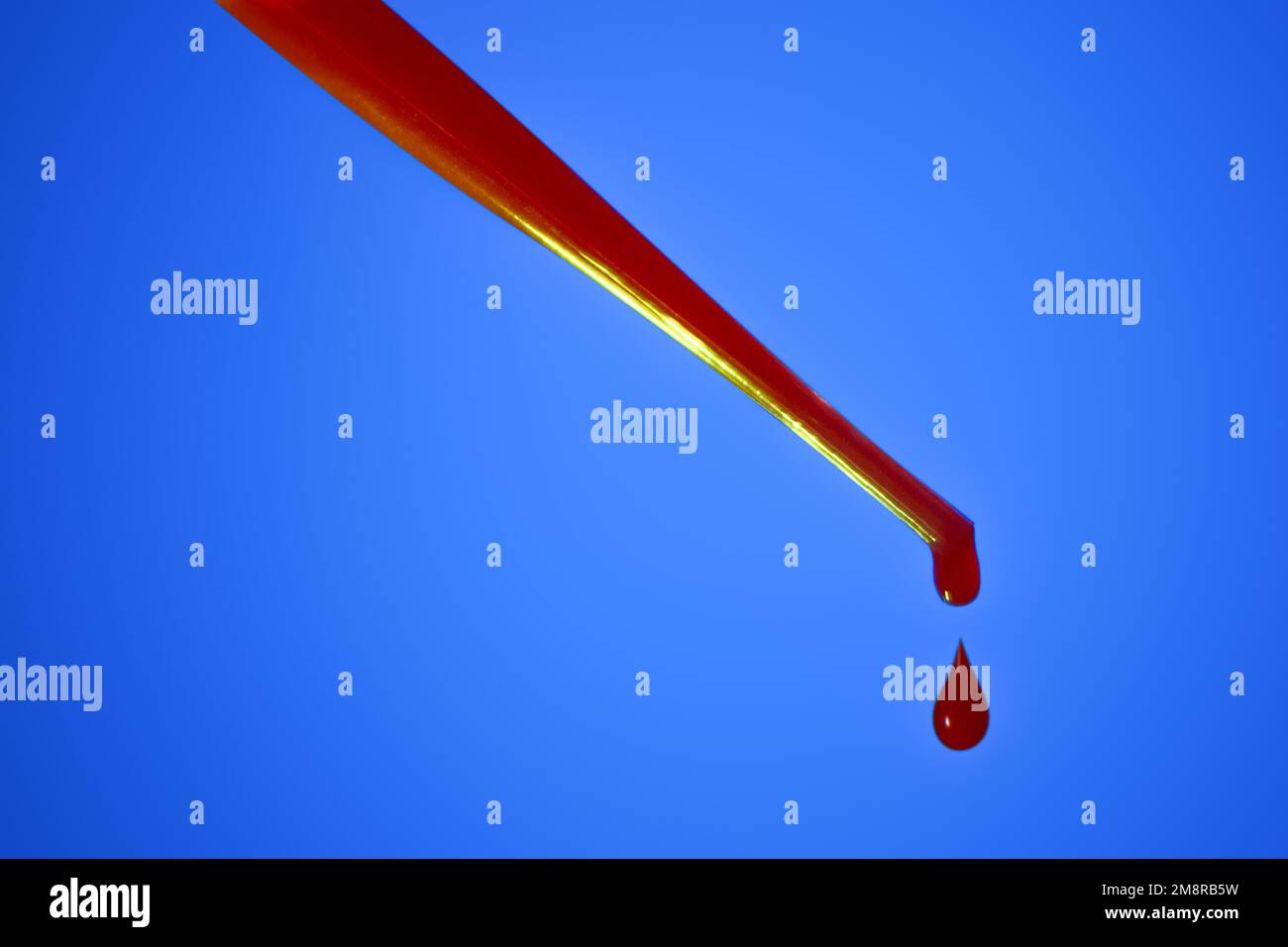 A drop of blood. Pipette. On a blue background. Dripping red liquid. A ...