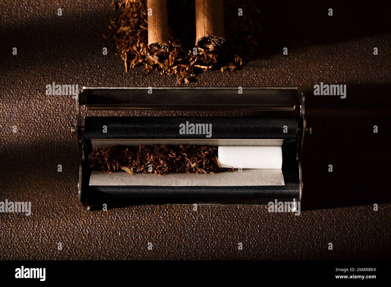Rolling machine, cigarillos, scattered tobacco on background, cigarette ...