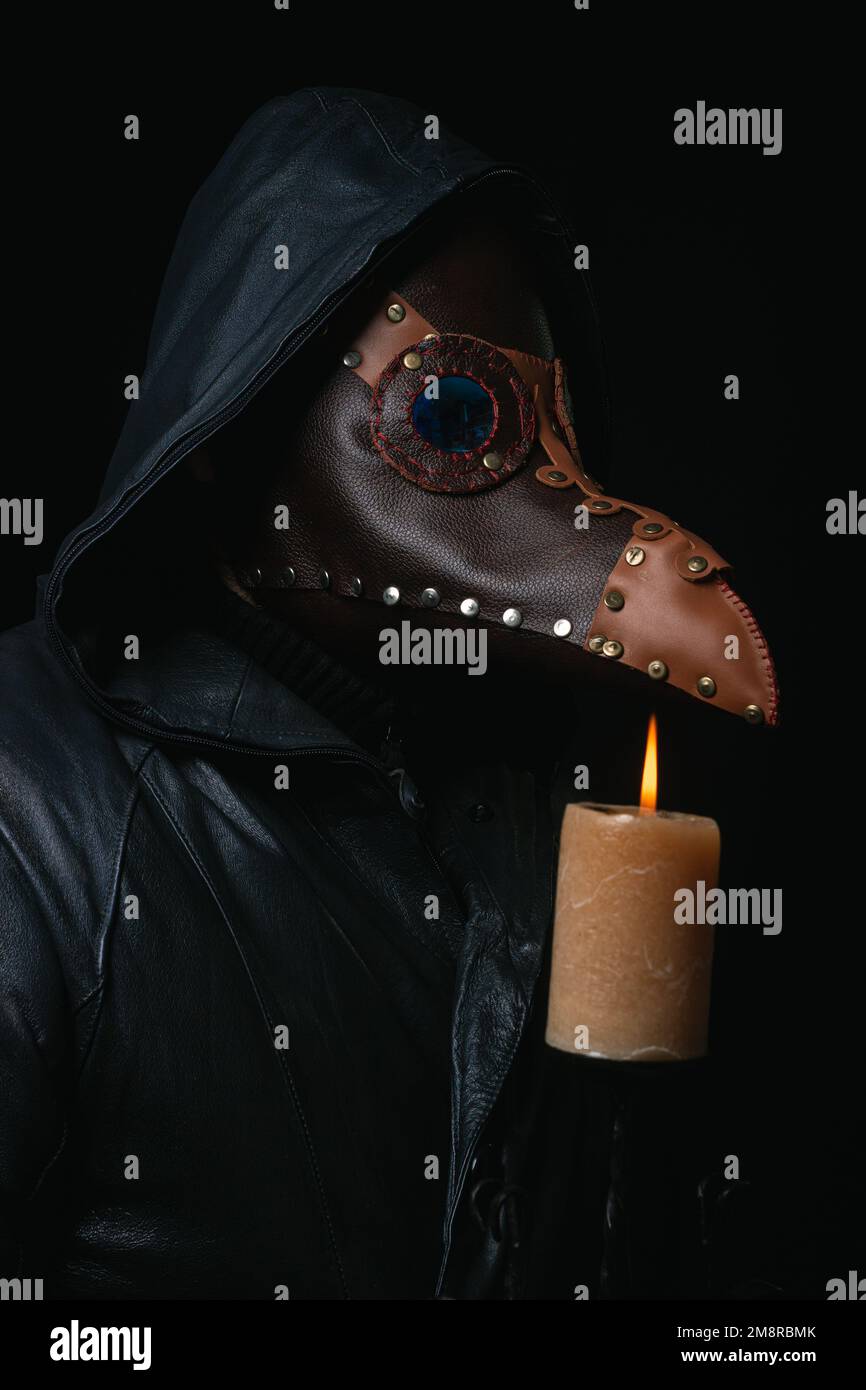 Plague doctor with crow-like mask and candle isolated on black ...
