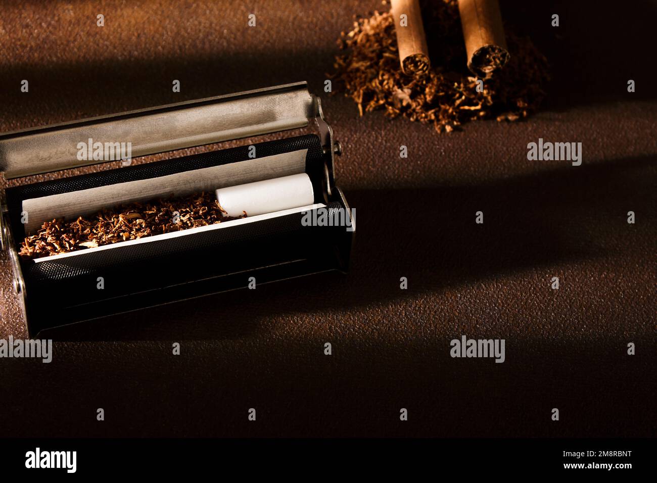 Hand-rolled cigarette, rolling machine, cigarillos, scattered tobacco ...