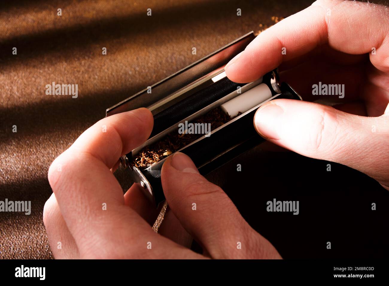 Hand-rolled cigarette, rolling machine, scattered tobacco on background ...