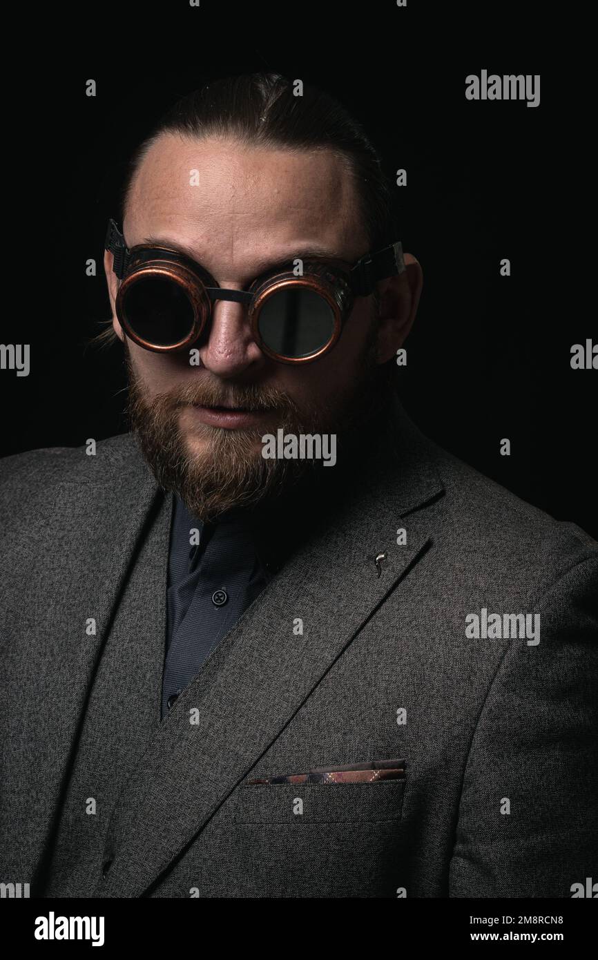 charismatic man in a classic suit and steampunk goggles on a black ...