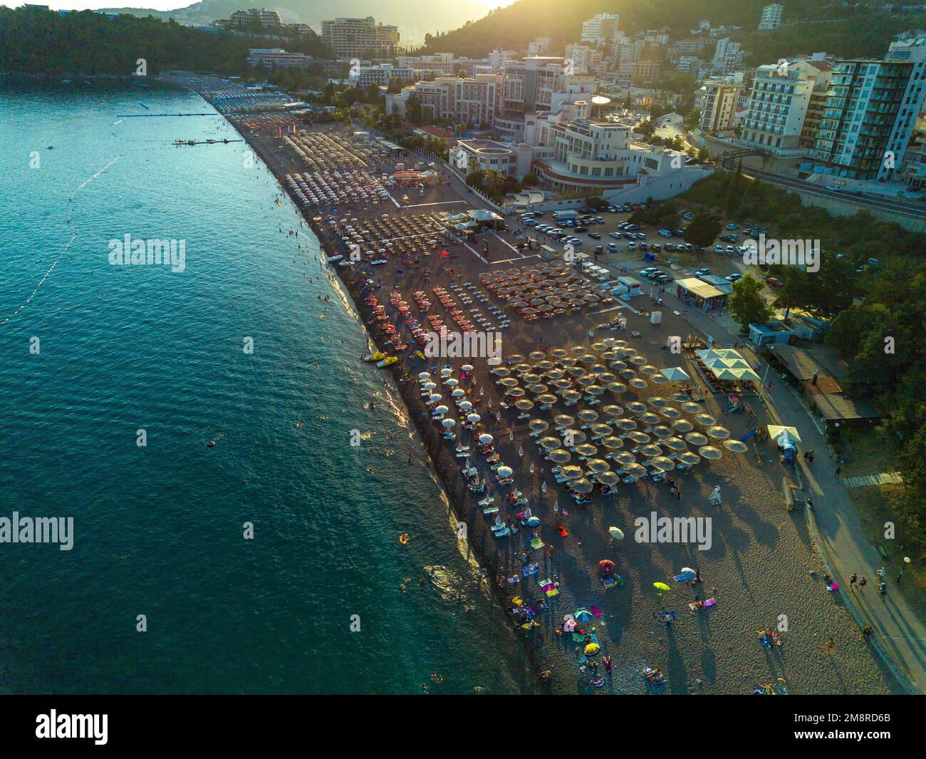 Wide sandy beach with sun umbrellas, plastic white sunbeds and people ...