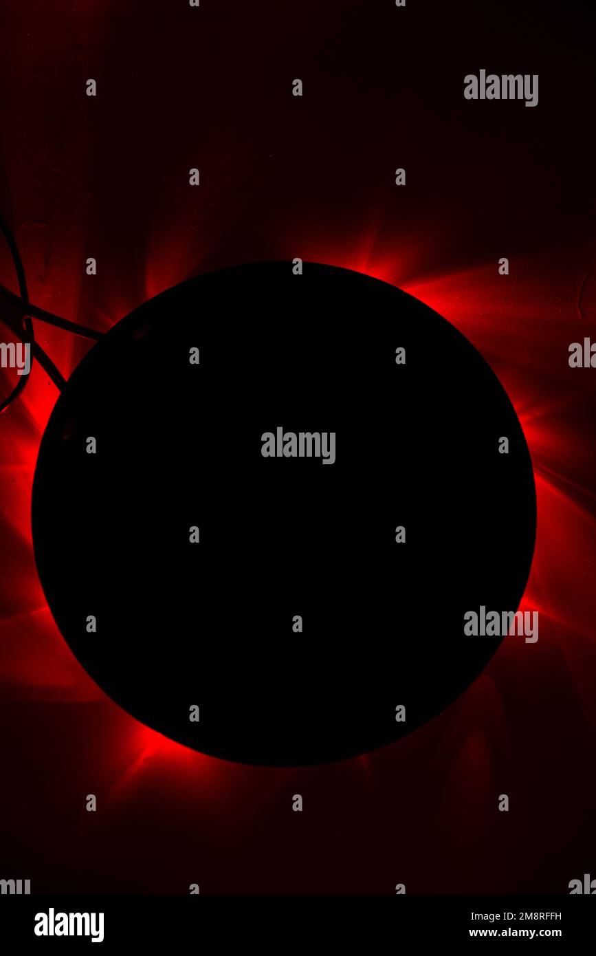 An abstract image of a black baking pan under which a red light shines ...