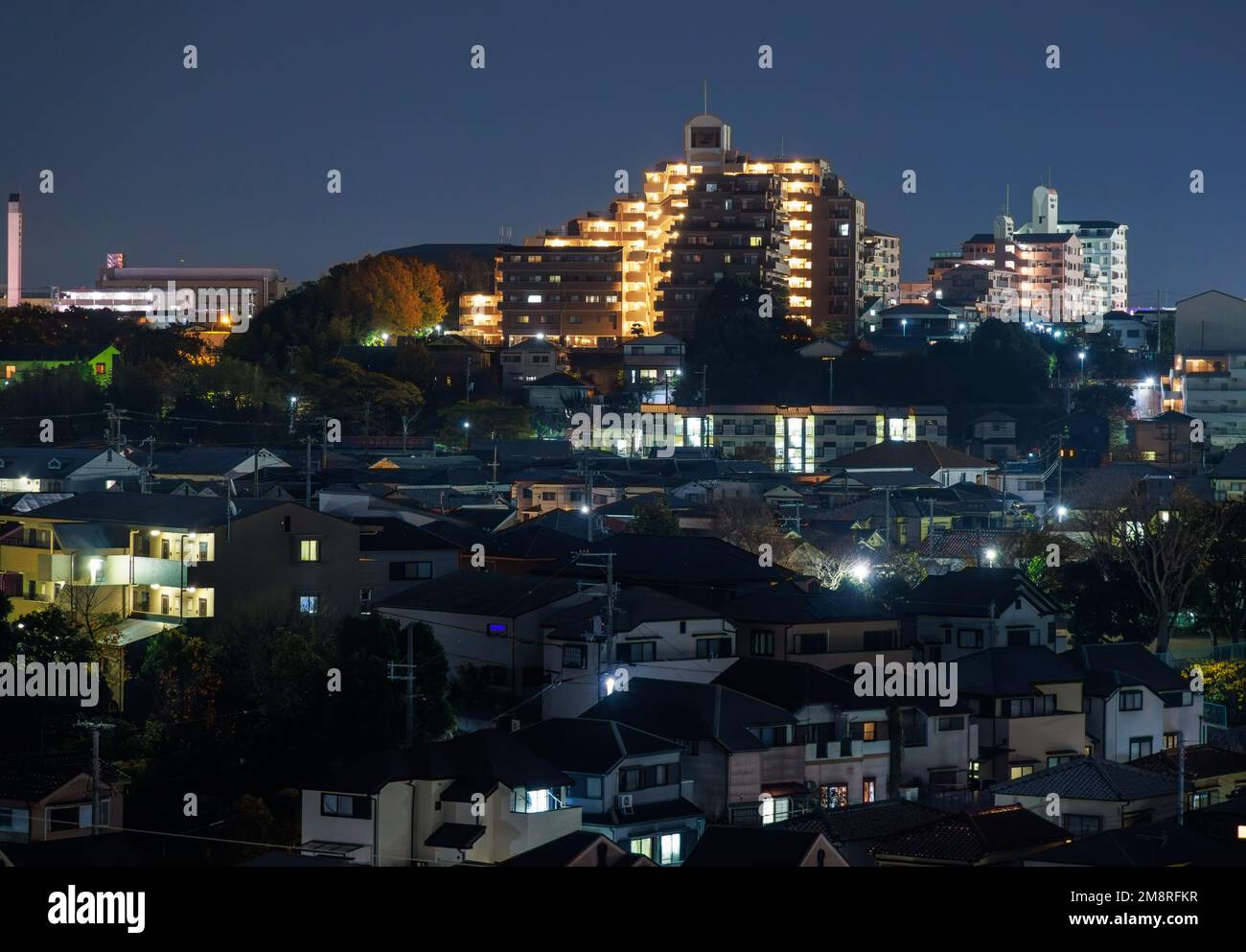 Tall apartment building on hill over residential neighborhood at night ...