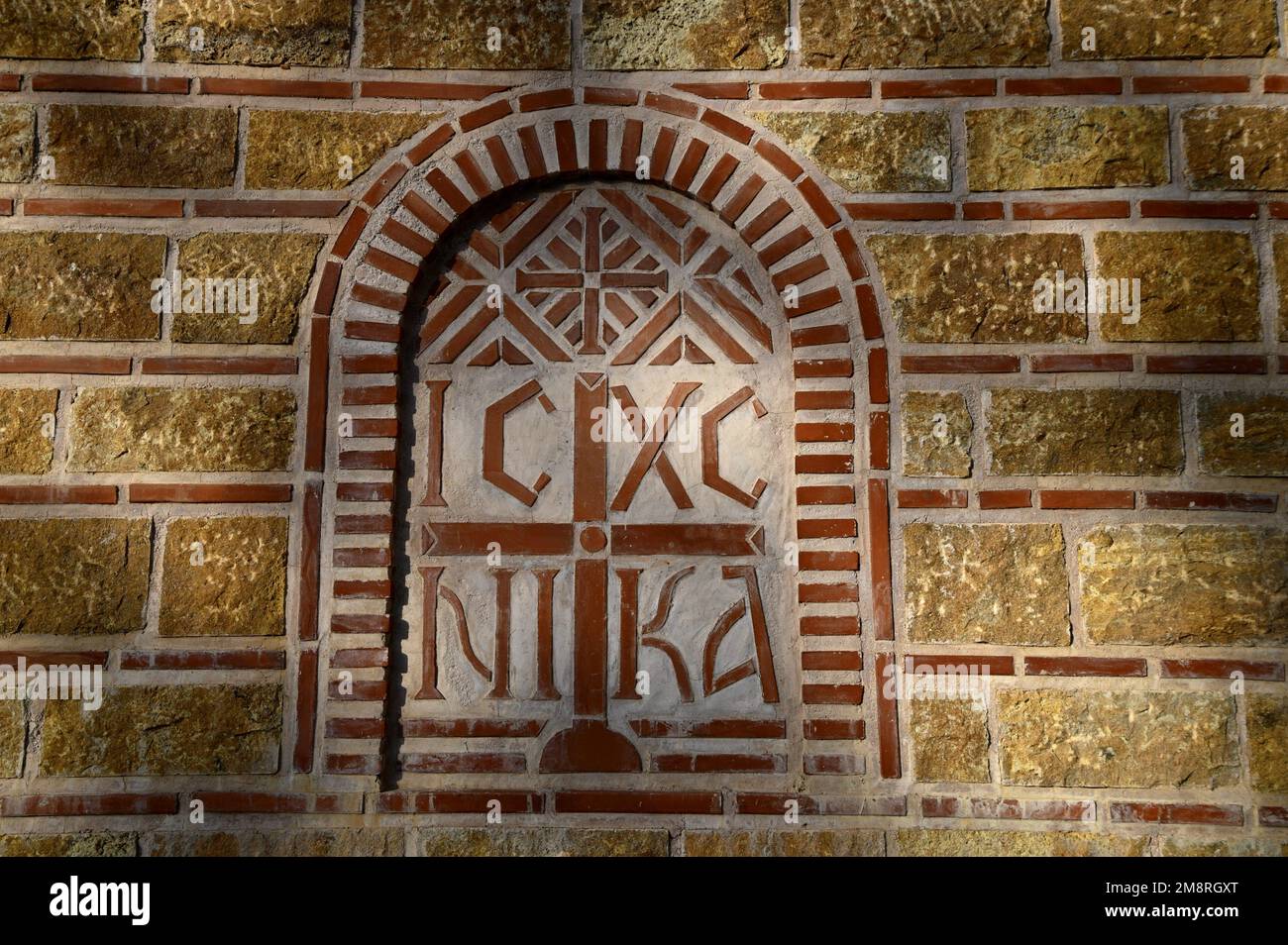 Handcrafted brick and clay tile wall with religious symbols at Aghios ...