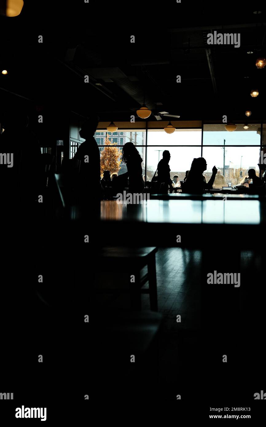 A vertical silhouette shot of a cafeteria with people sitting Stock ...
