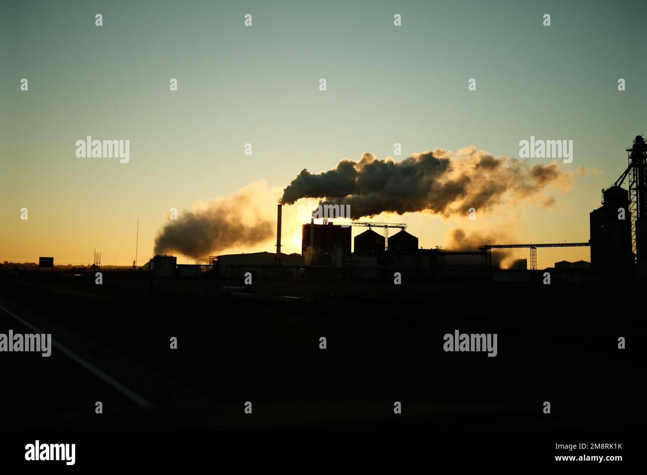 A silhouette shot of a factory emitting smoke from its chimneys located ...