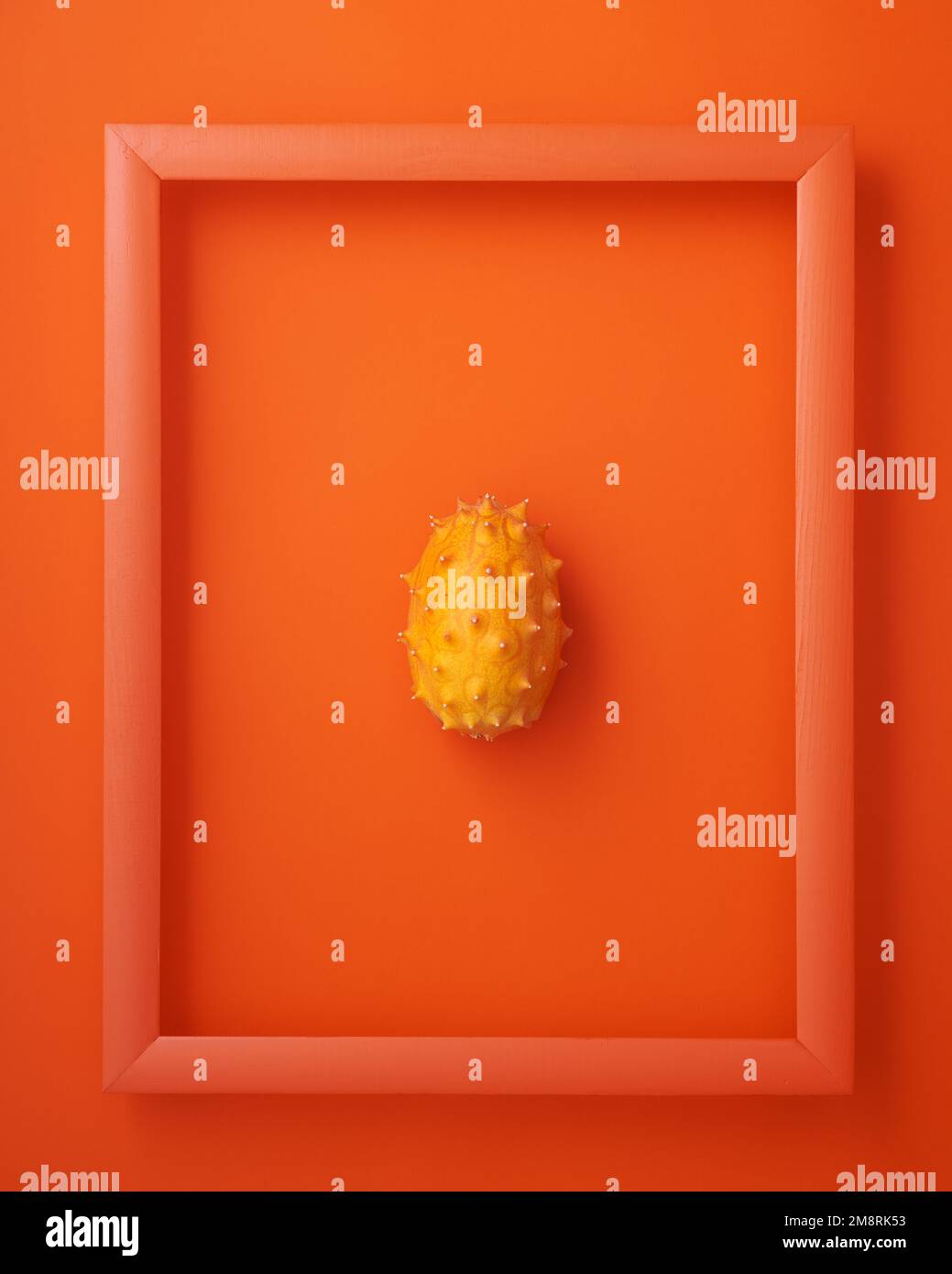 Horned melon in wooden picture frame on orange background Stock Photo ...