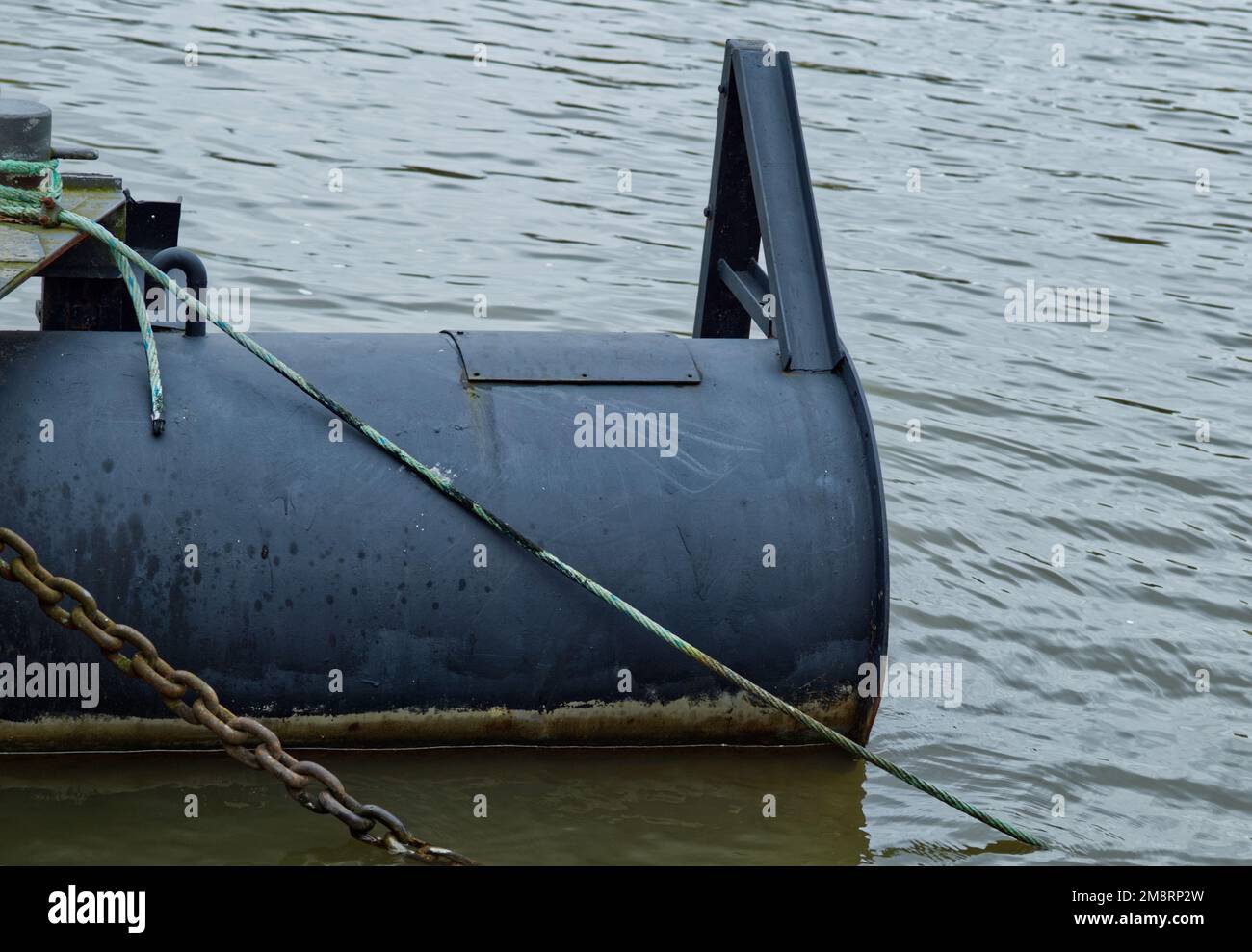 Detail of a barreled bouy in blue and black colors swimming in a river ...