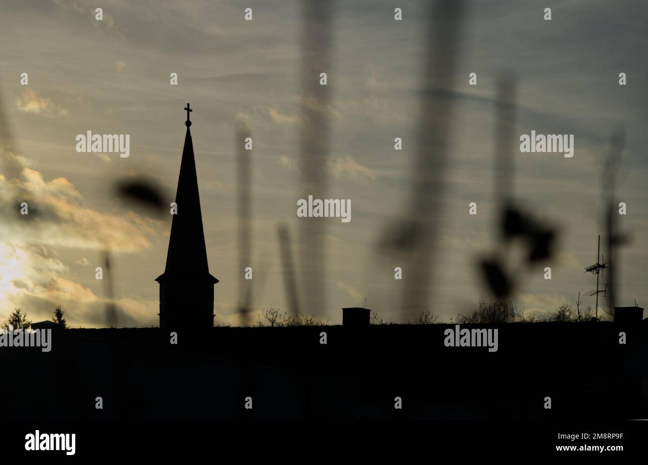 Atmospheric silhouette of a roof with several chimneys and a church ...