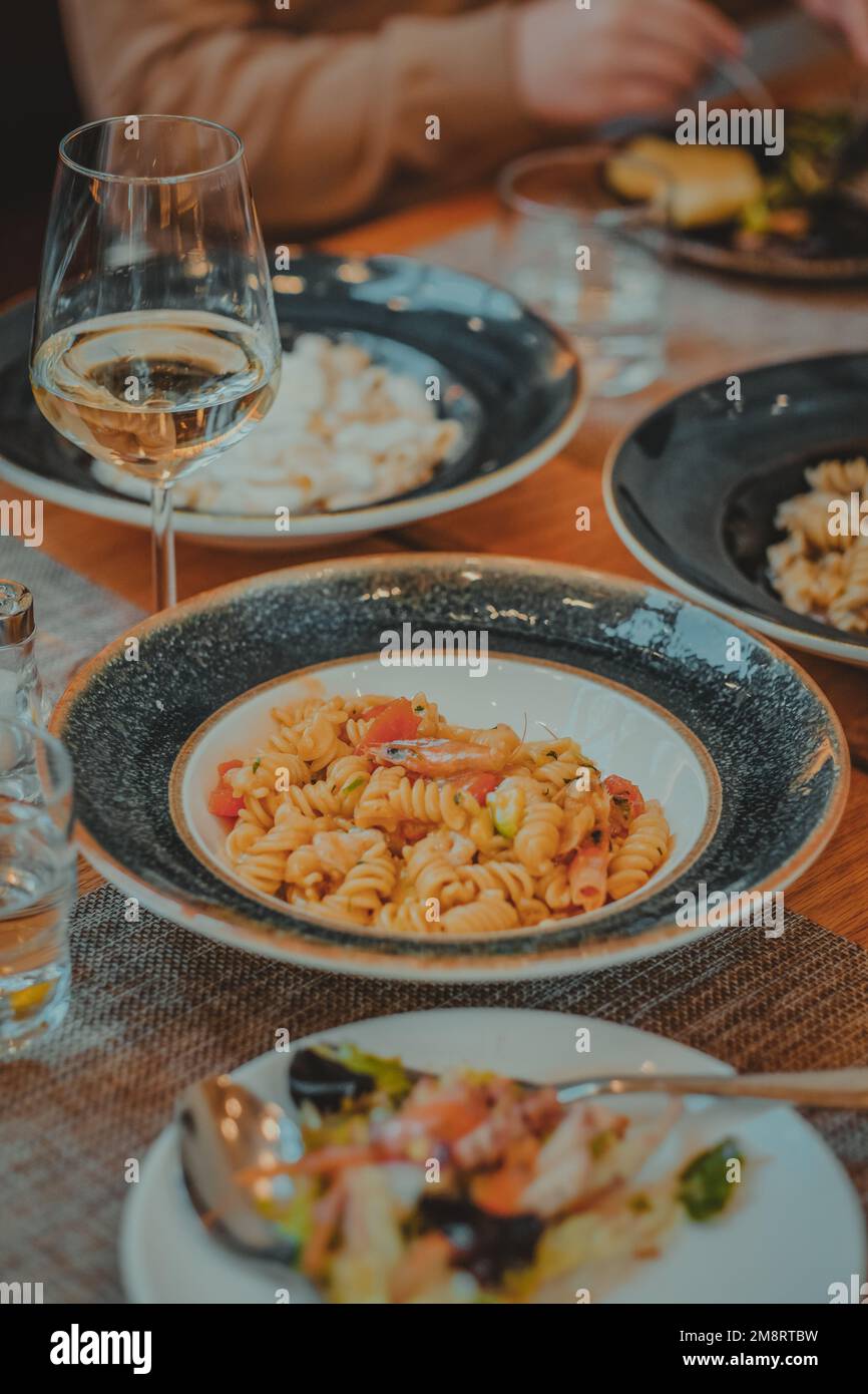 Italian restaurant table with dinner of pasta salad and a glass of wine ...