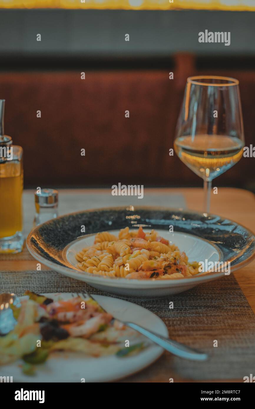 Italian restaurant table with dinner of pasta salad and a glass of wine ...