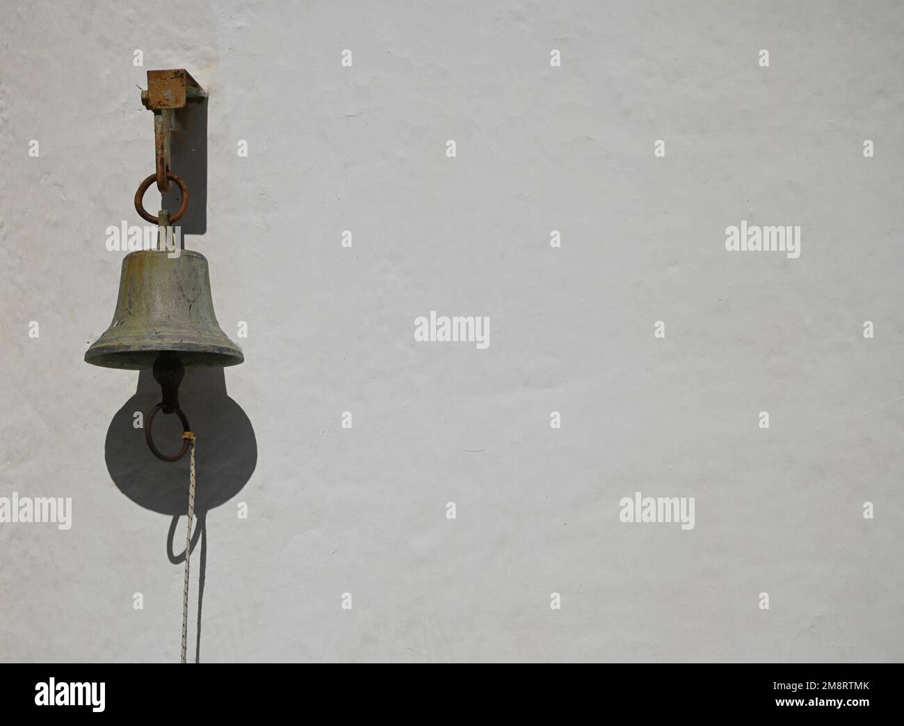 Cast iron bell on the whitewashed wall of Timios Stavros a traditional ...