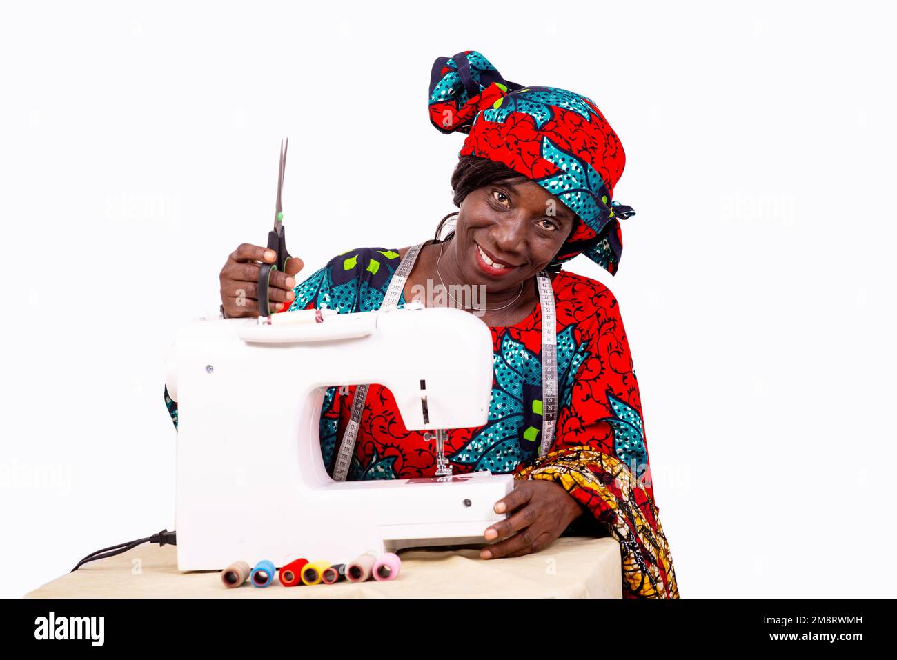 a dressmaker in traditional dress sitting on a white background looking ...