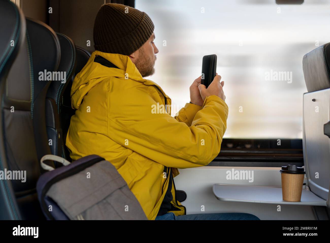 Man in yellow jacket takes photo with his phone through the window ...