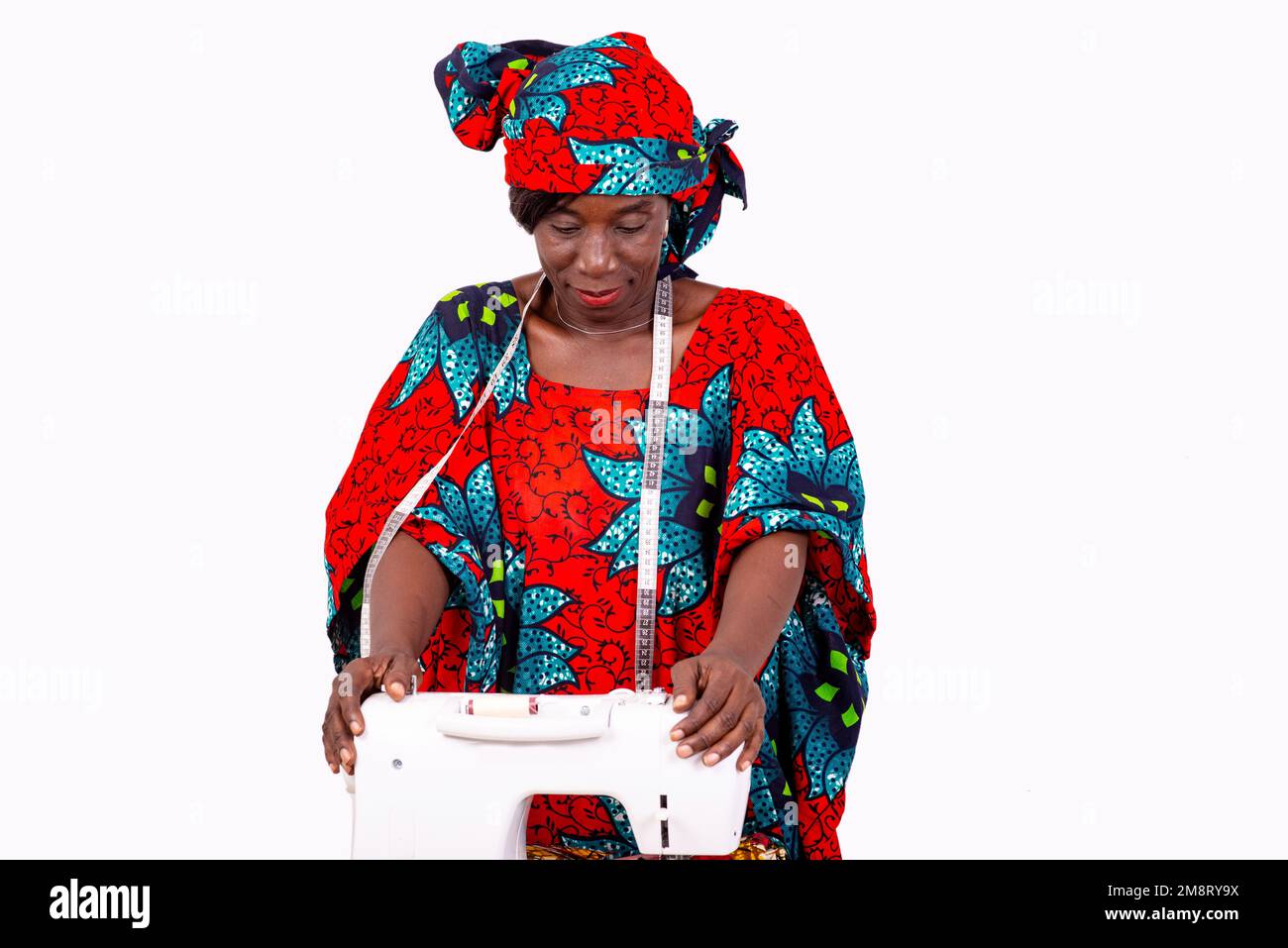 a dressmaker in traditional dress standing against white background ...