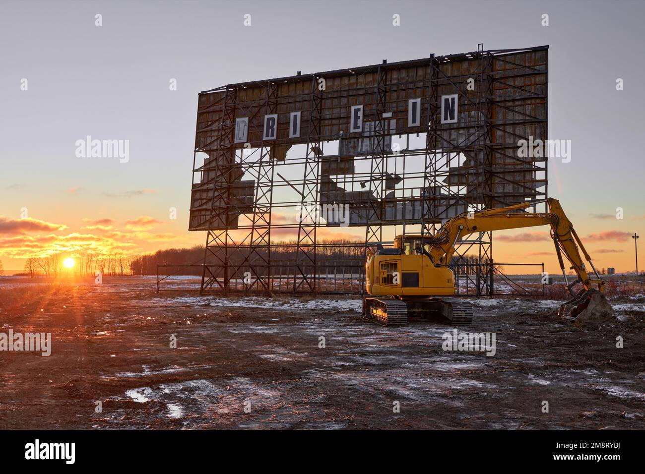 Abandoned outdoor drive in movie theater at sunset with excavator ready ...