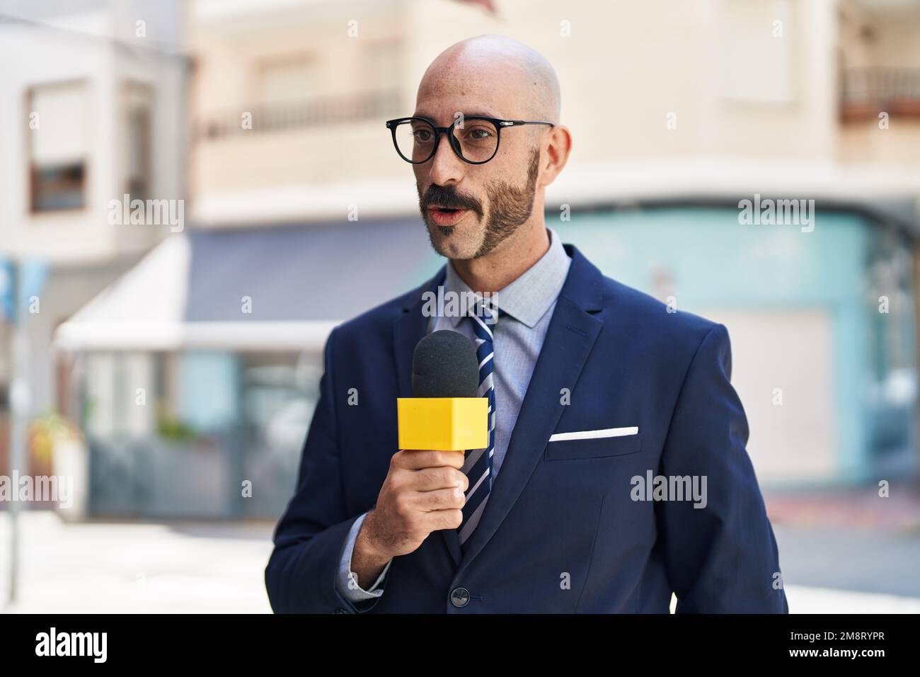 Young hispanic man reporter working using microphone at street Stock ...