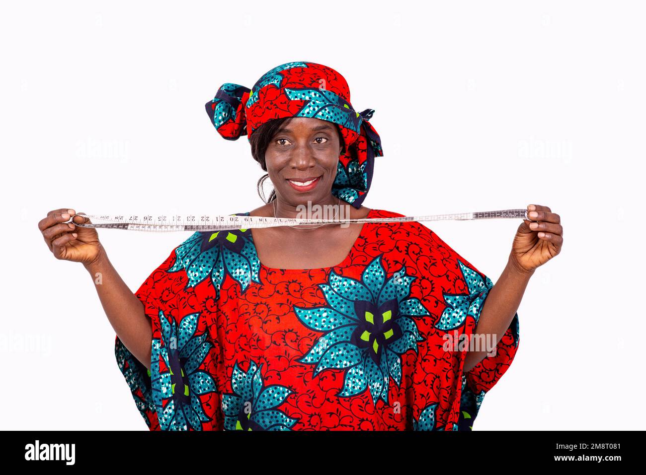 a dressmaker in traditional attire standing against white background ...