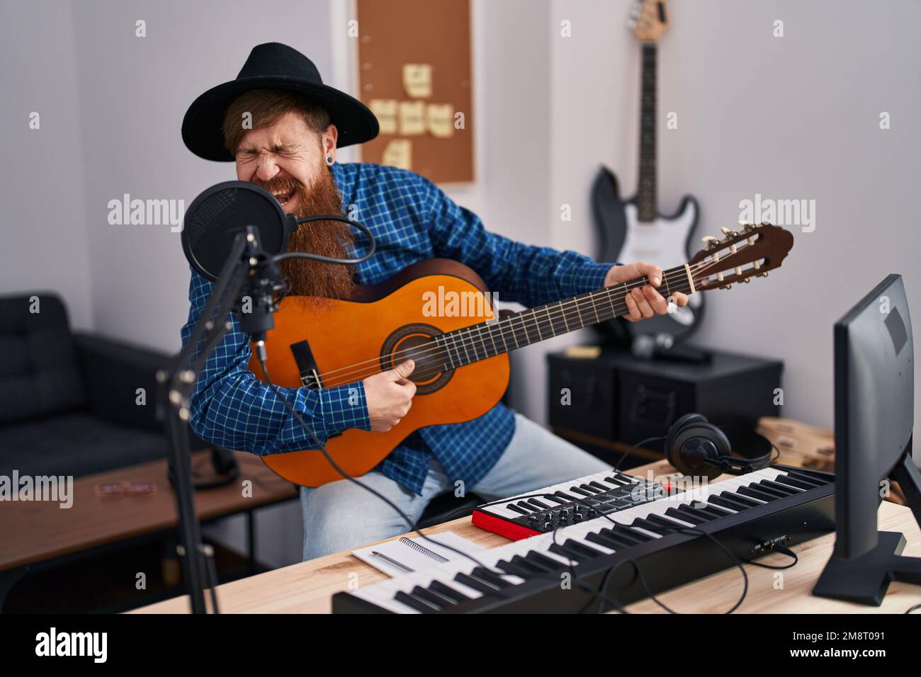Young redhead man musician singing song playing classical guitar at ...