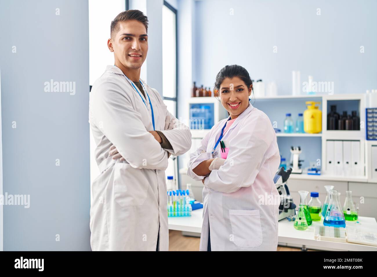 Man and woman scientists partners standing with arms crossed gesture at ...
