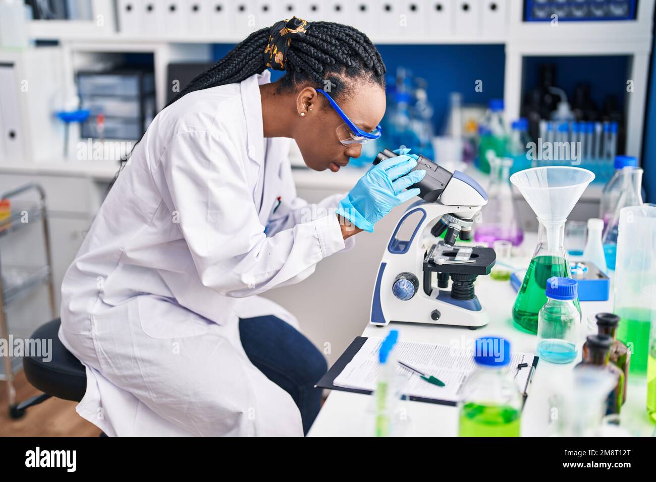 African american woman scientist using microscope at laboratory Stock Photo - Alamy
