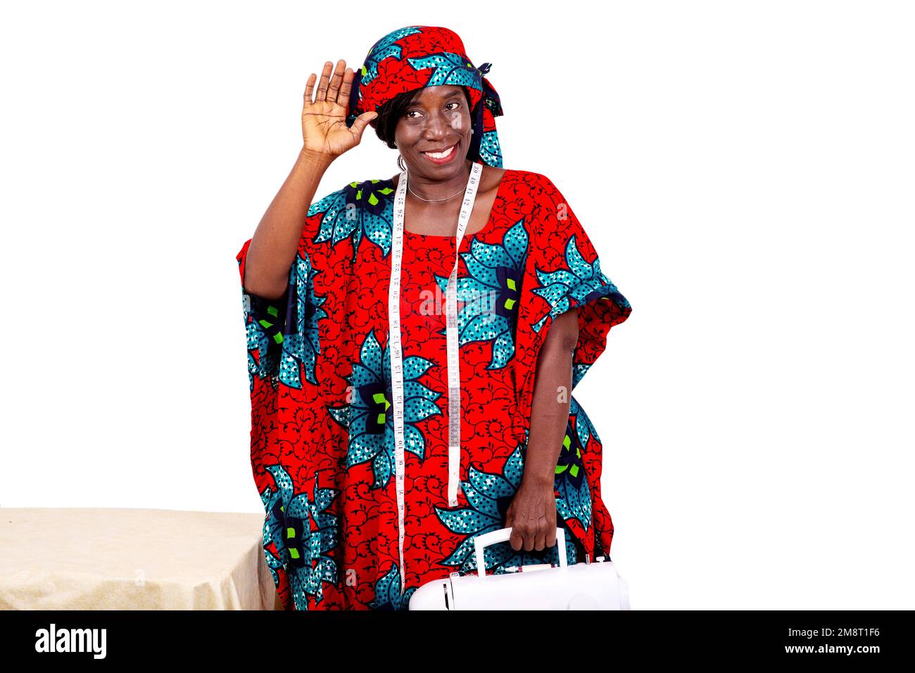 a dressmaker in traditional attire standing against white background ...