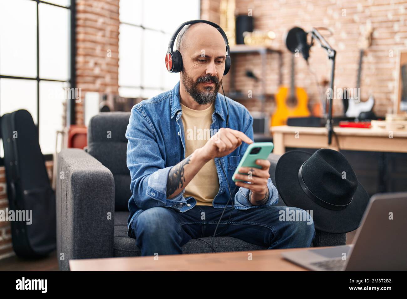 Young bald man musician listening to music at music studio Stock Photo ...