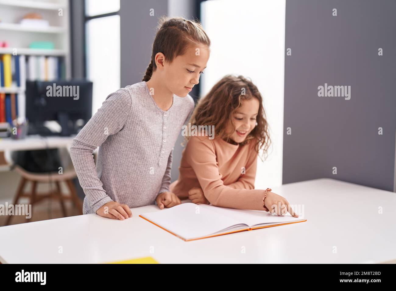 Two kids students reading book studying at classroom Stock Photo - Alamy