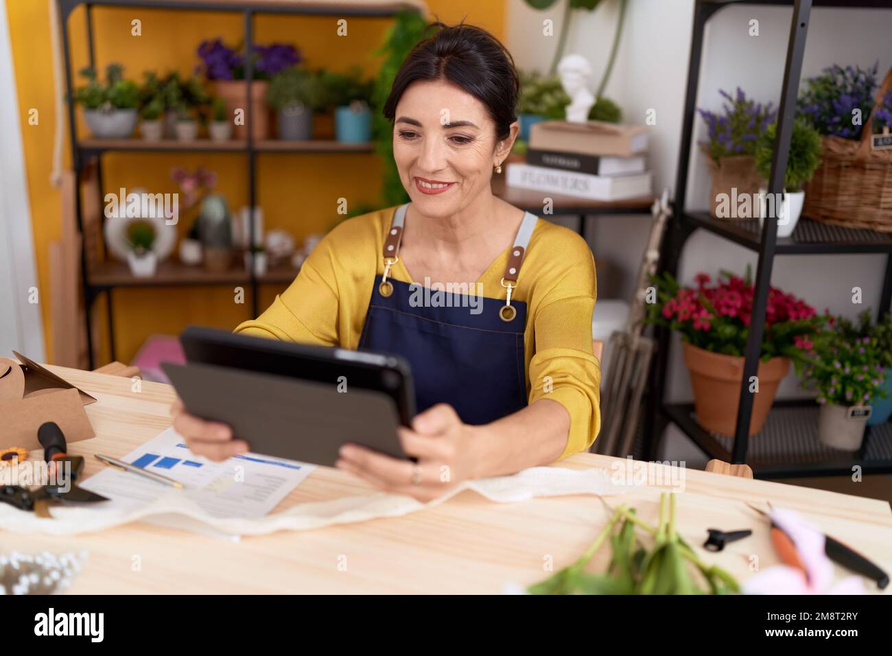 Middle age hispanic woman florist smiling confident using touchpad at flower shop Stock Photo ...