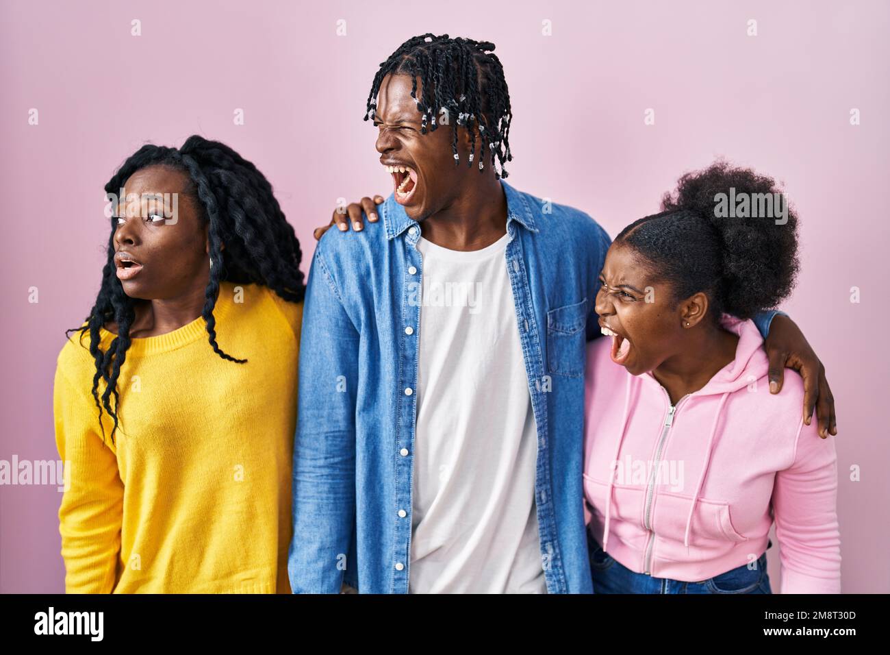 Group of three young black people standing together over pink ...