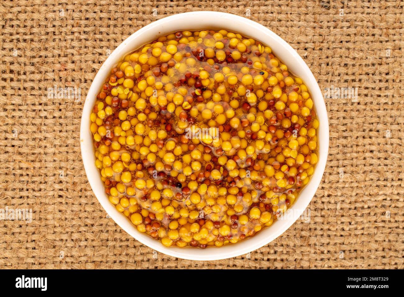 French mustard in a white saucer on a jute cloth, macro, top view Stock ...