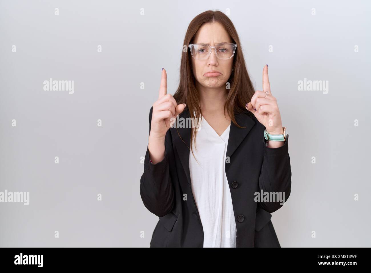 Beautiful brunette woman wearing business jacket and glasses pointing ...