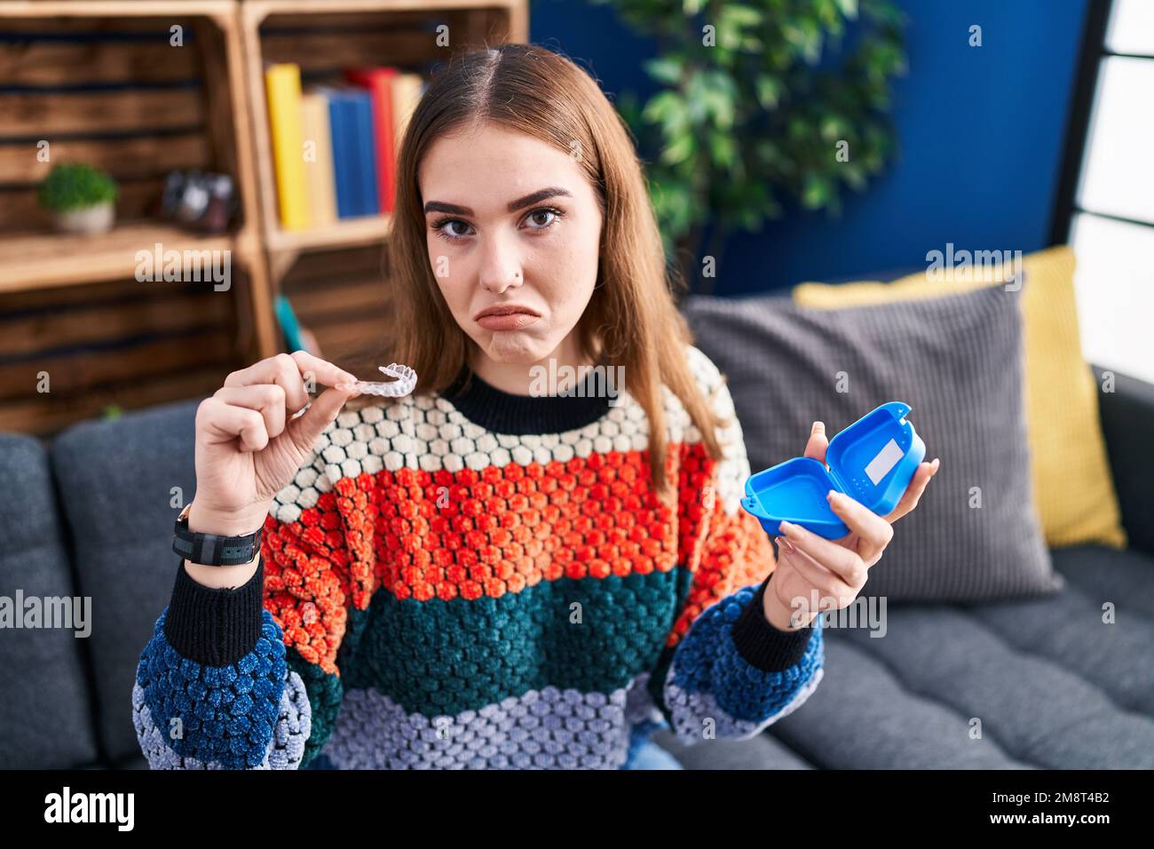 Young hispanic girl holding invisible aligner orthodontic depressed and ...