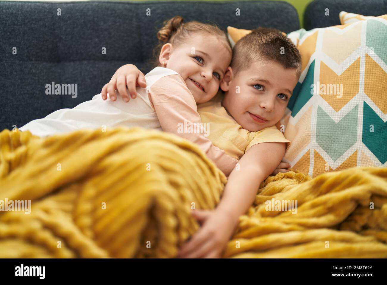Two kids hugging each other lying on sofa at home Stock Photo - Alamy
