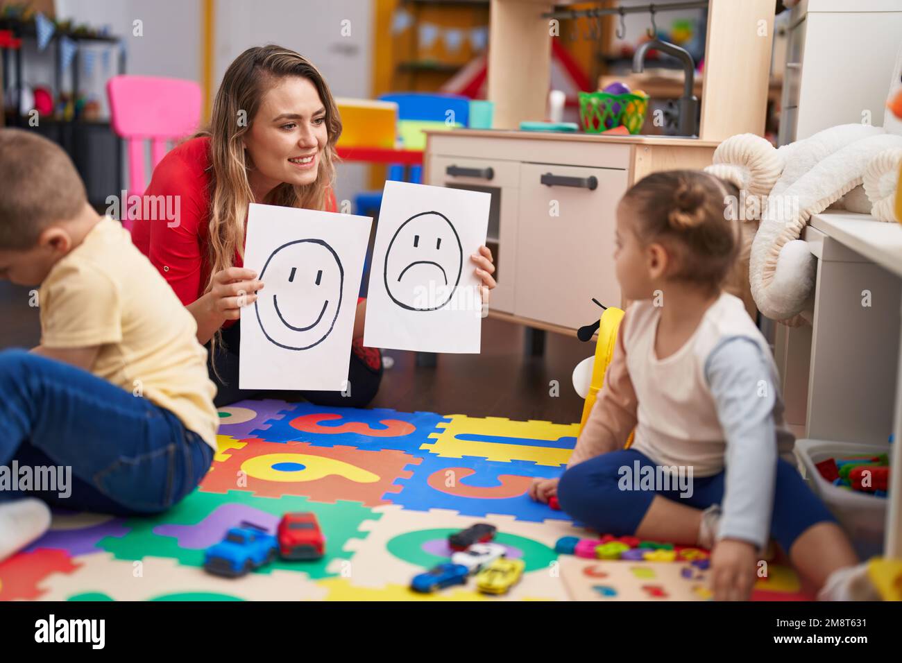 Teacher with boy and girl sitting on table having emotion therapy at ...