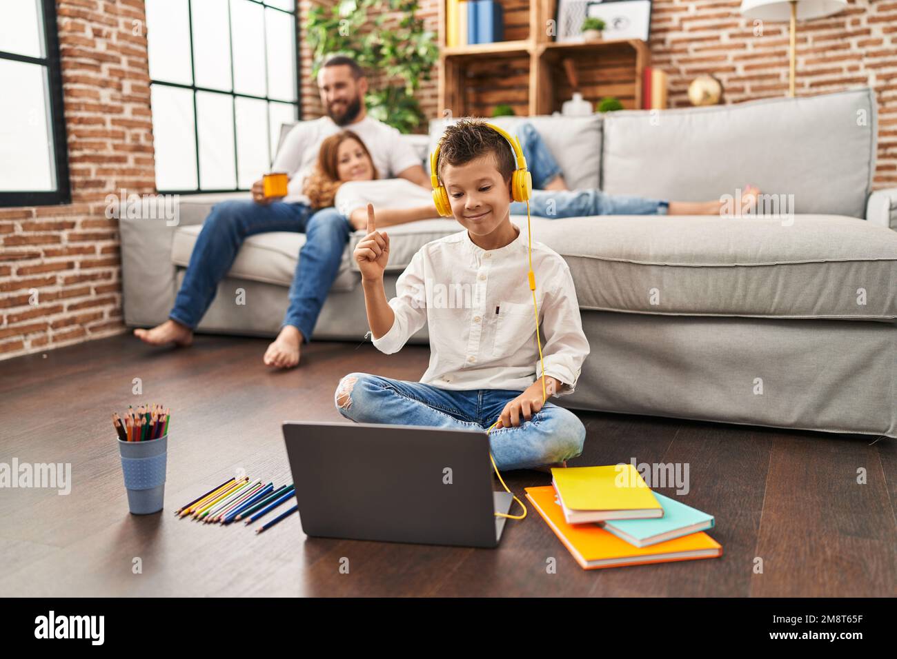 Family of three doing homework at home smiling with an idea or question ...