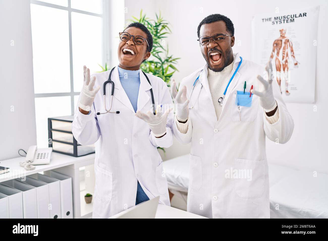 Young african american doctors working at medical clinic crazy and mad ...