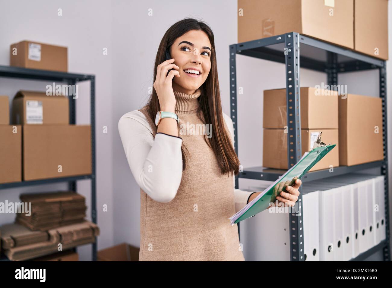 Young beautiful hispanic woman ecommerce business worker talking on ...