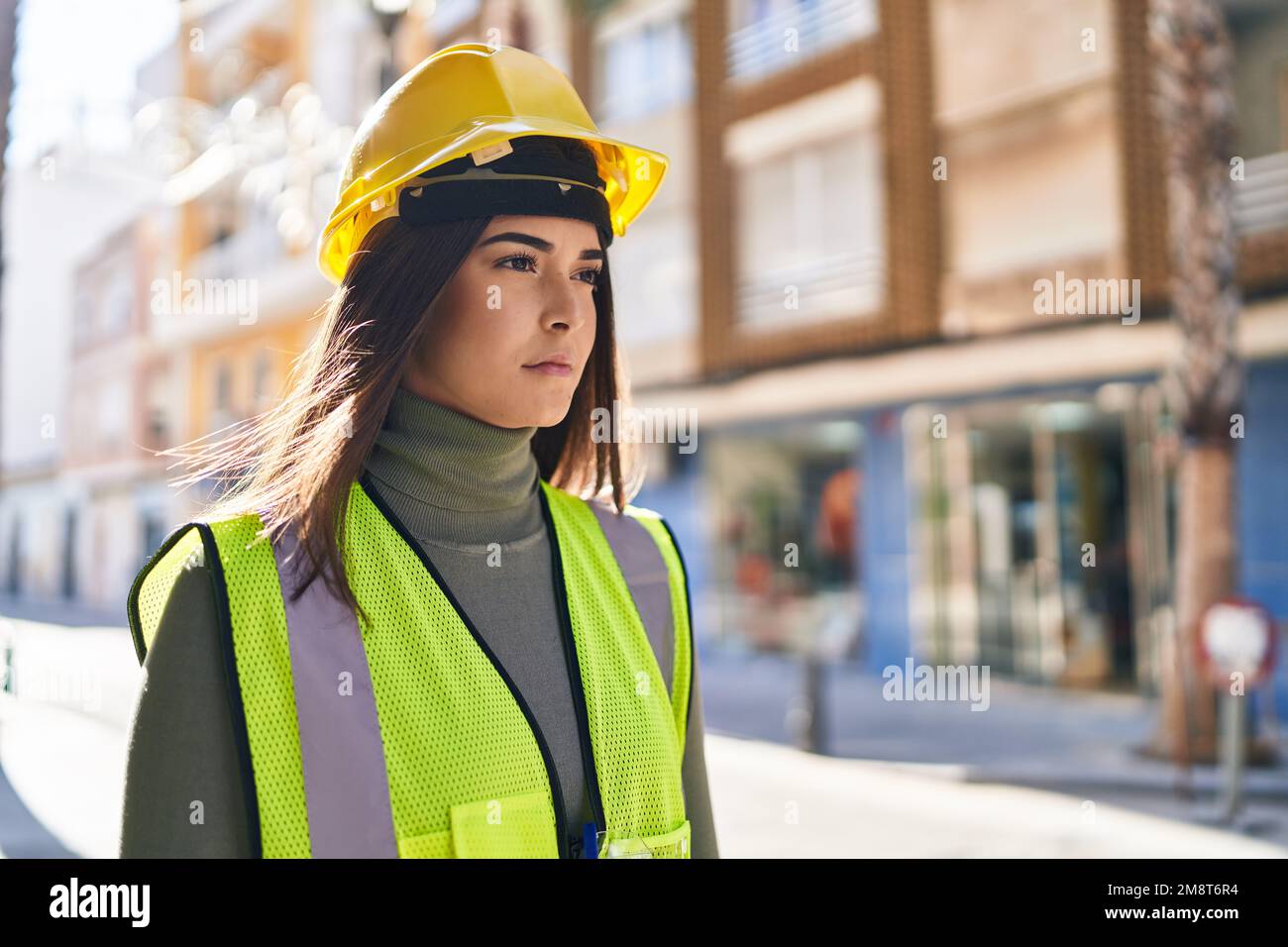 Young beautiful hispanic woman architect standing with serious ...
