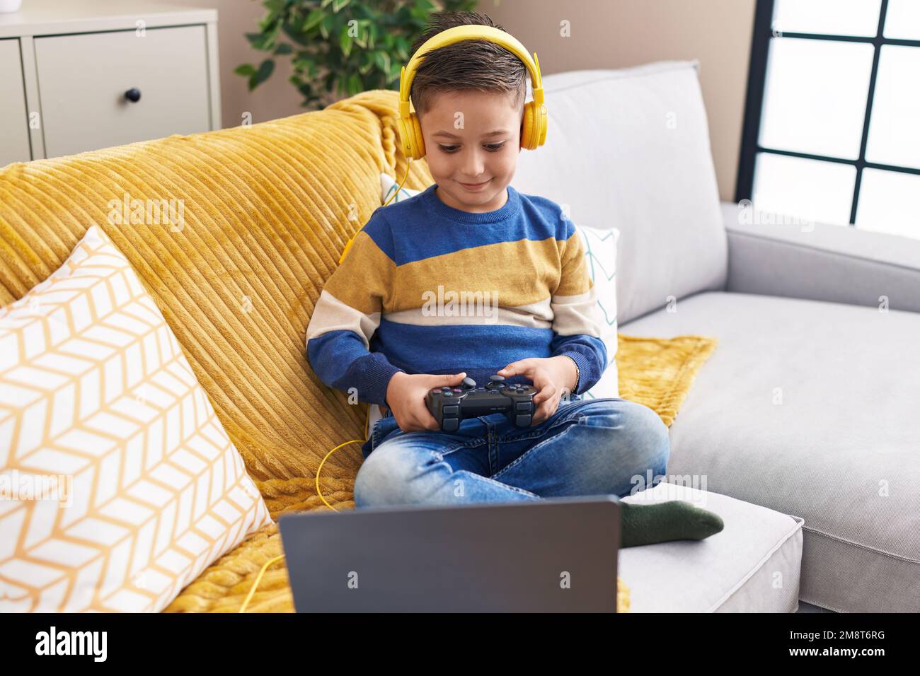 Adorable hispanic boy playing video game sitting on sofa at home Stock ...