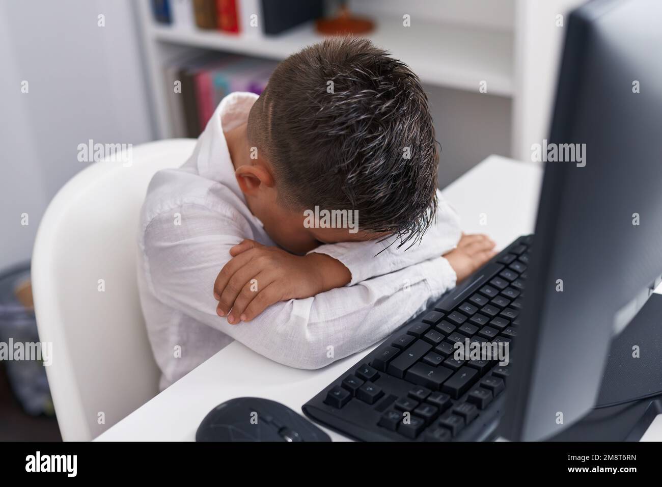 Adorable hispanic boy student using computer with stressed expression ...