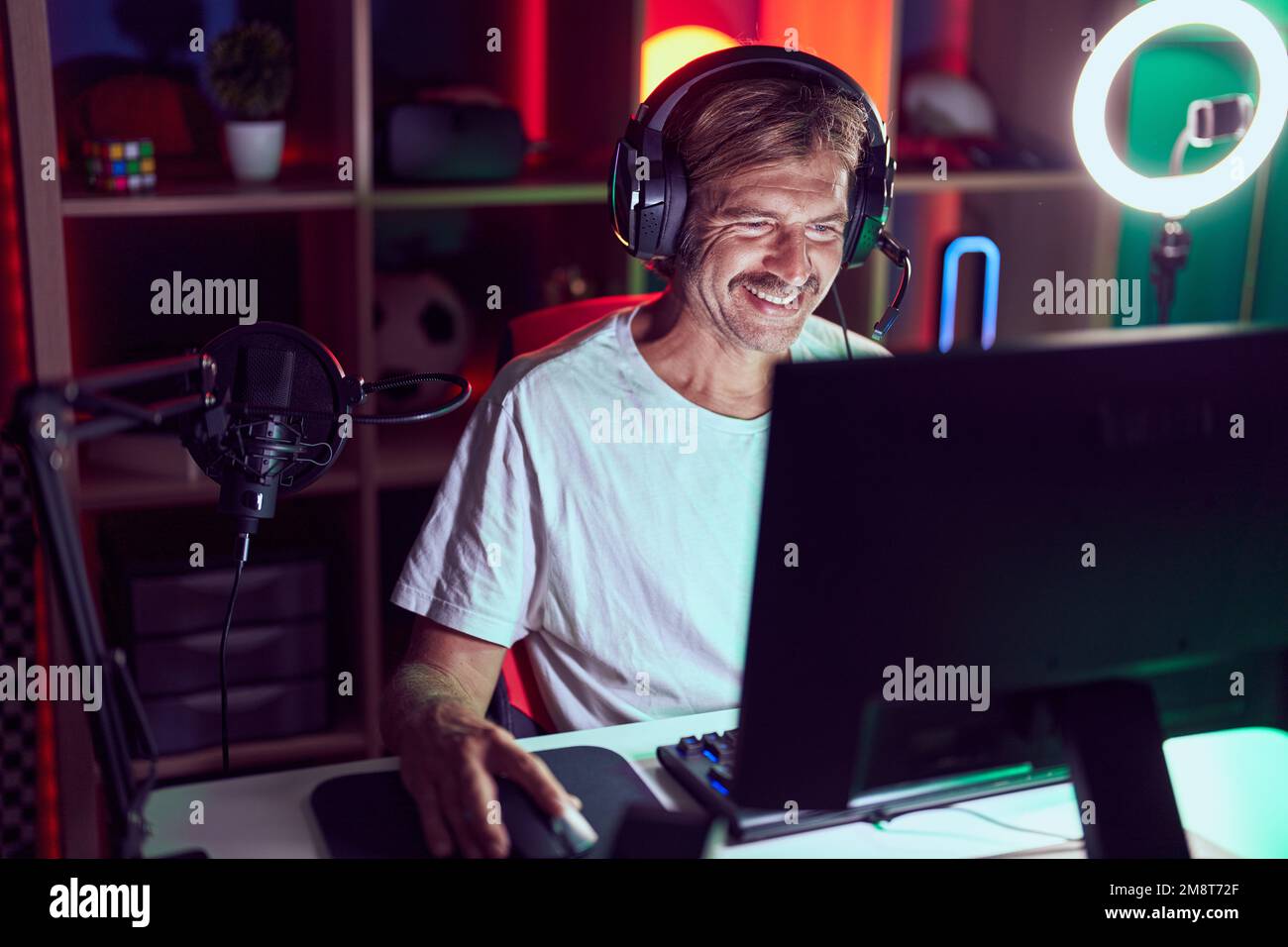 Young blond man streamer playing video game using computer at gaming ...
