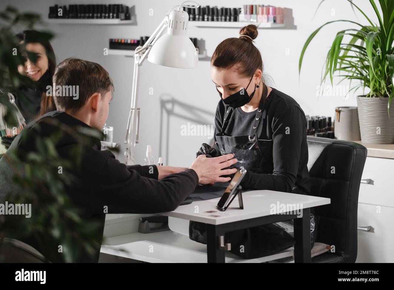 Male manicure. Female nail service master doing manicure for adult man ...