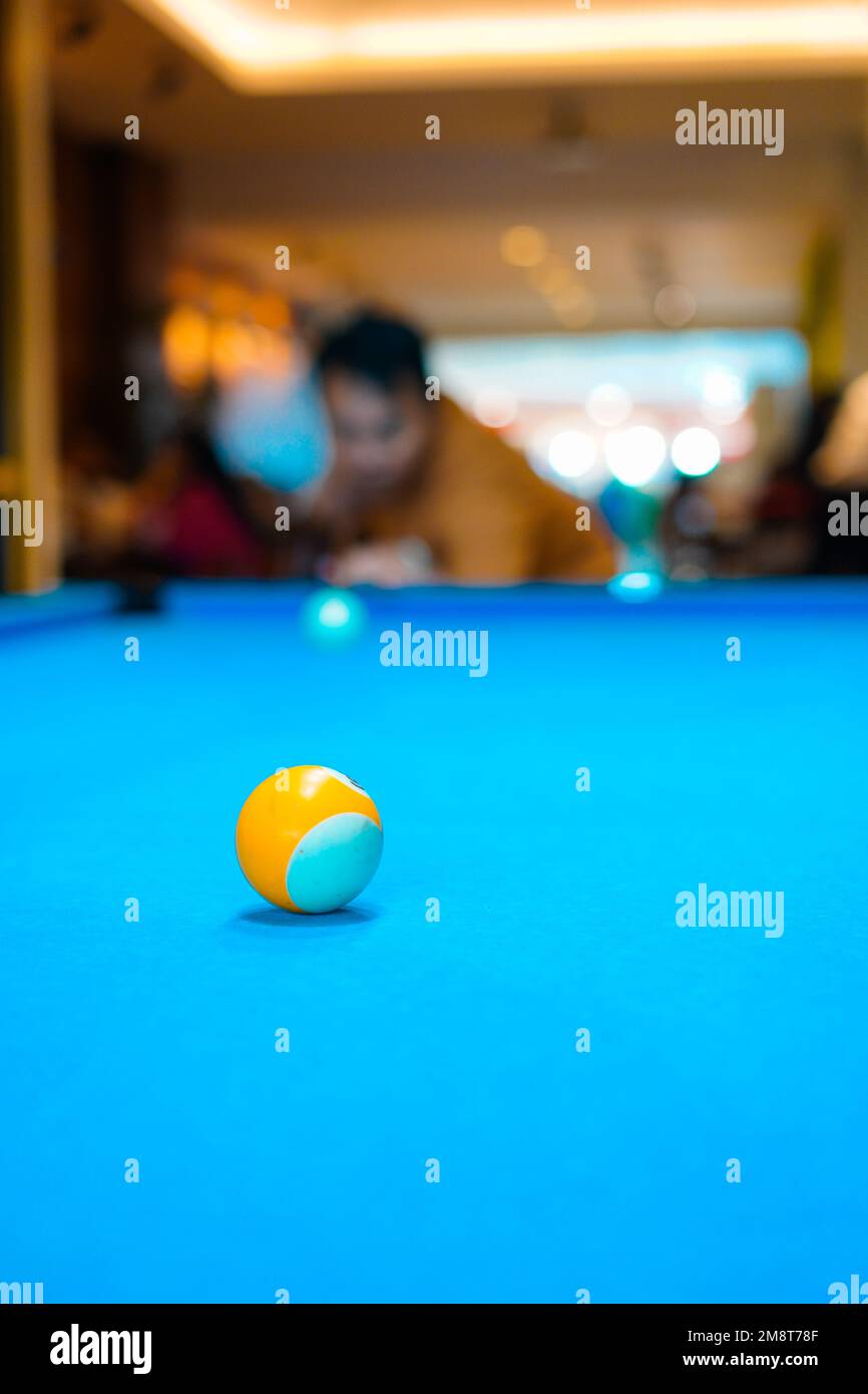 Player aiming cue in a billiard ball. Blurred person in the background ...