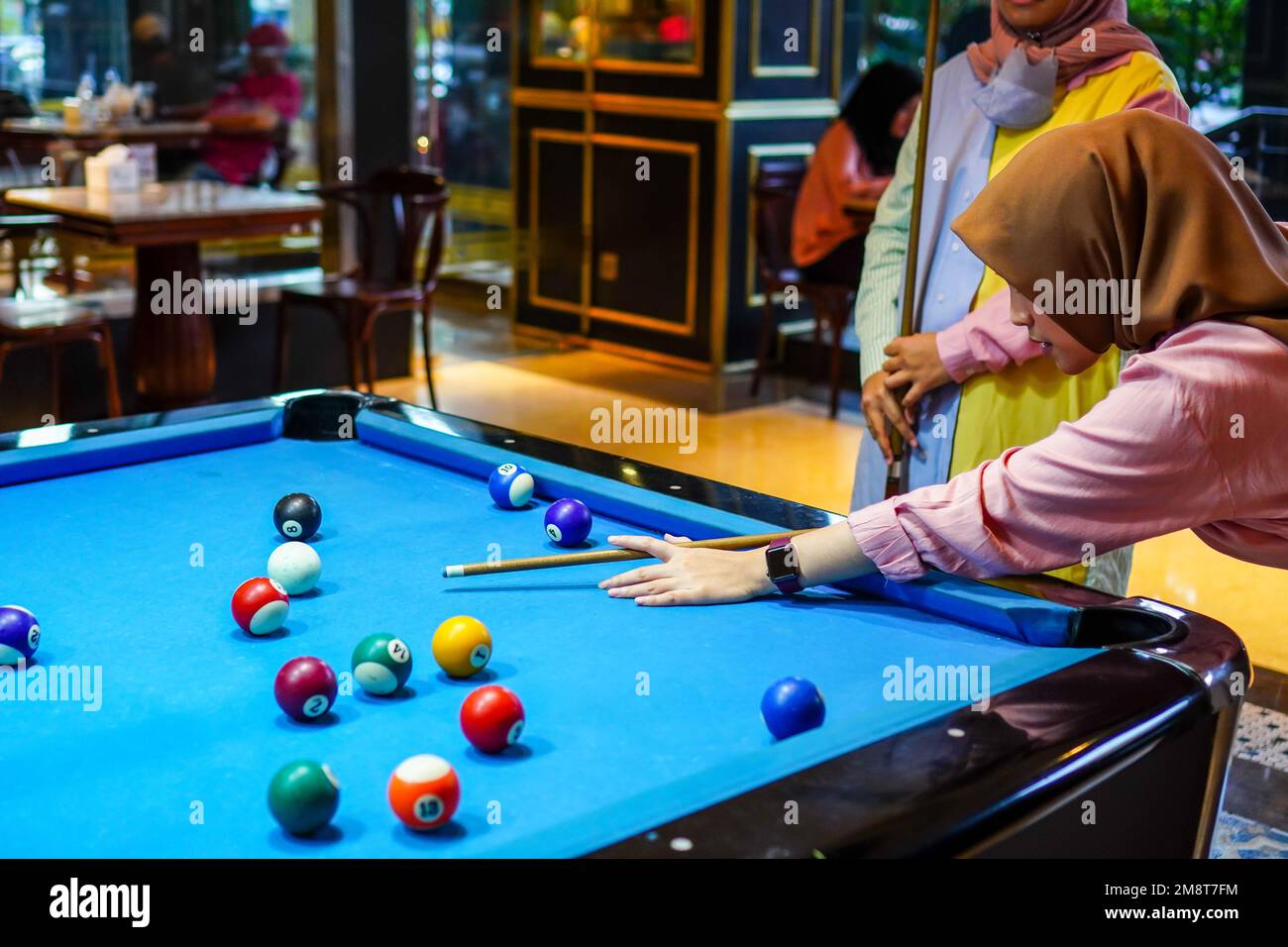 Woman in hijab playing billiards with friends Stock Photo - Alamy
