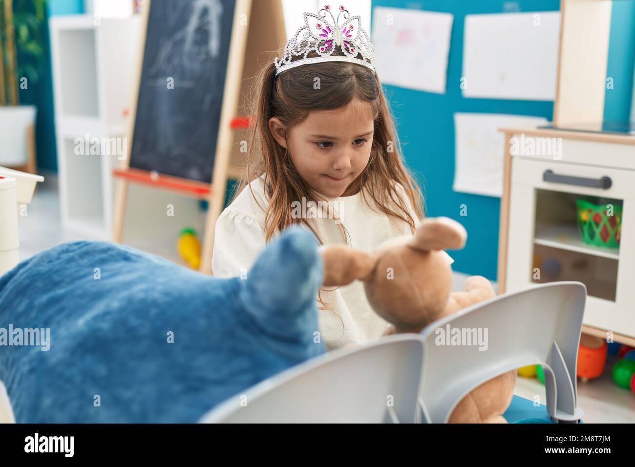 Adorable blonde girl wearing princess crown playing with rabbit doll at ...